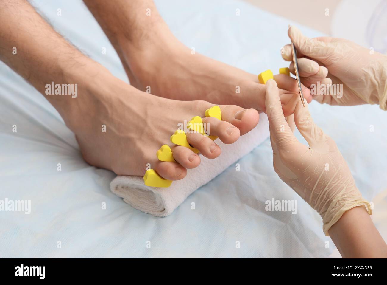 Young man getting professional pedicure with toe separator and file on ...