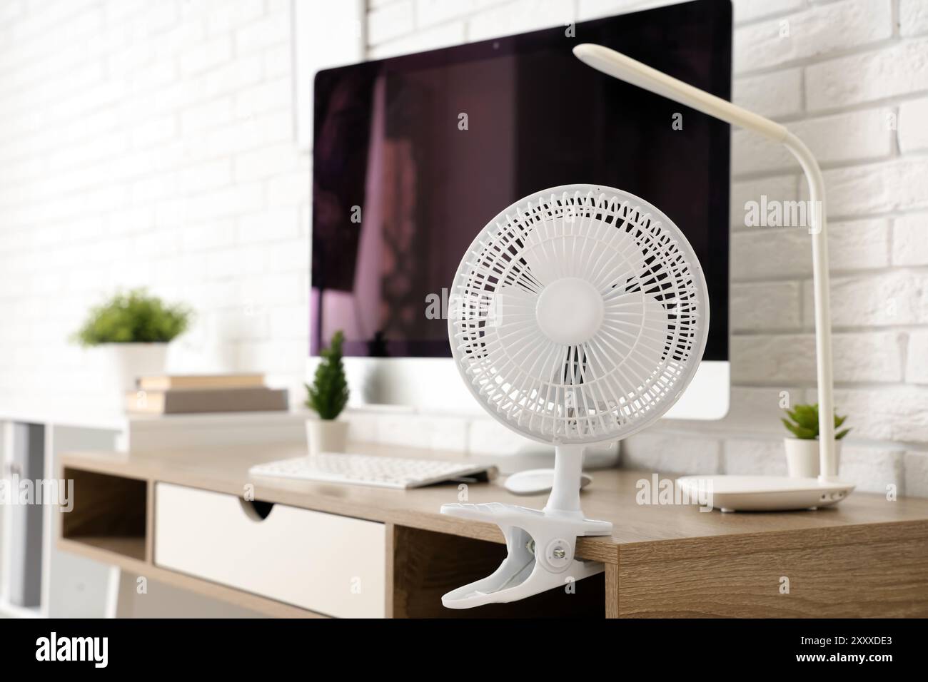 Modern electric fan on table near white brick wall in office Stock ...