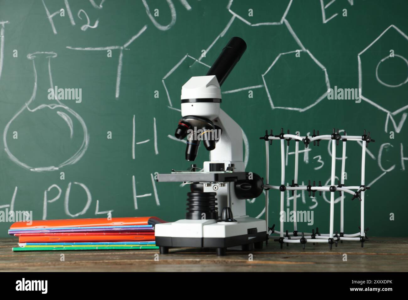 Modern microscope, copybooks and molecular model on wooden table near ...
