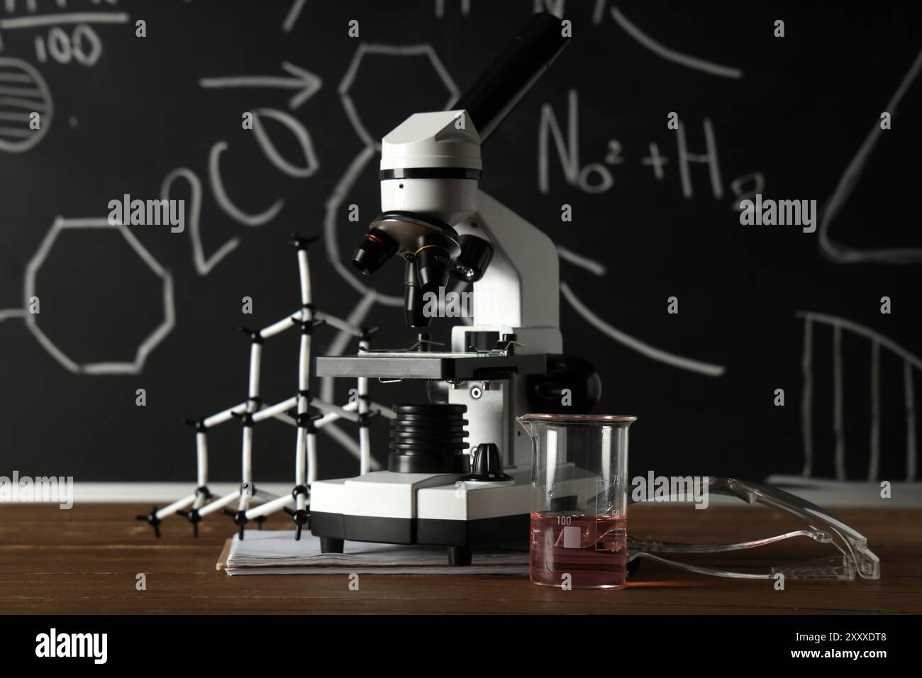 Modern microscope, molecular model and flask on wooden table near ...