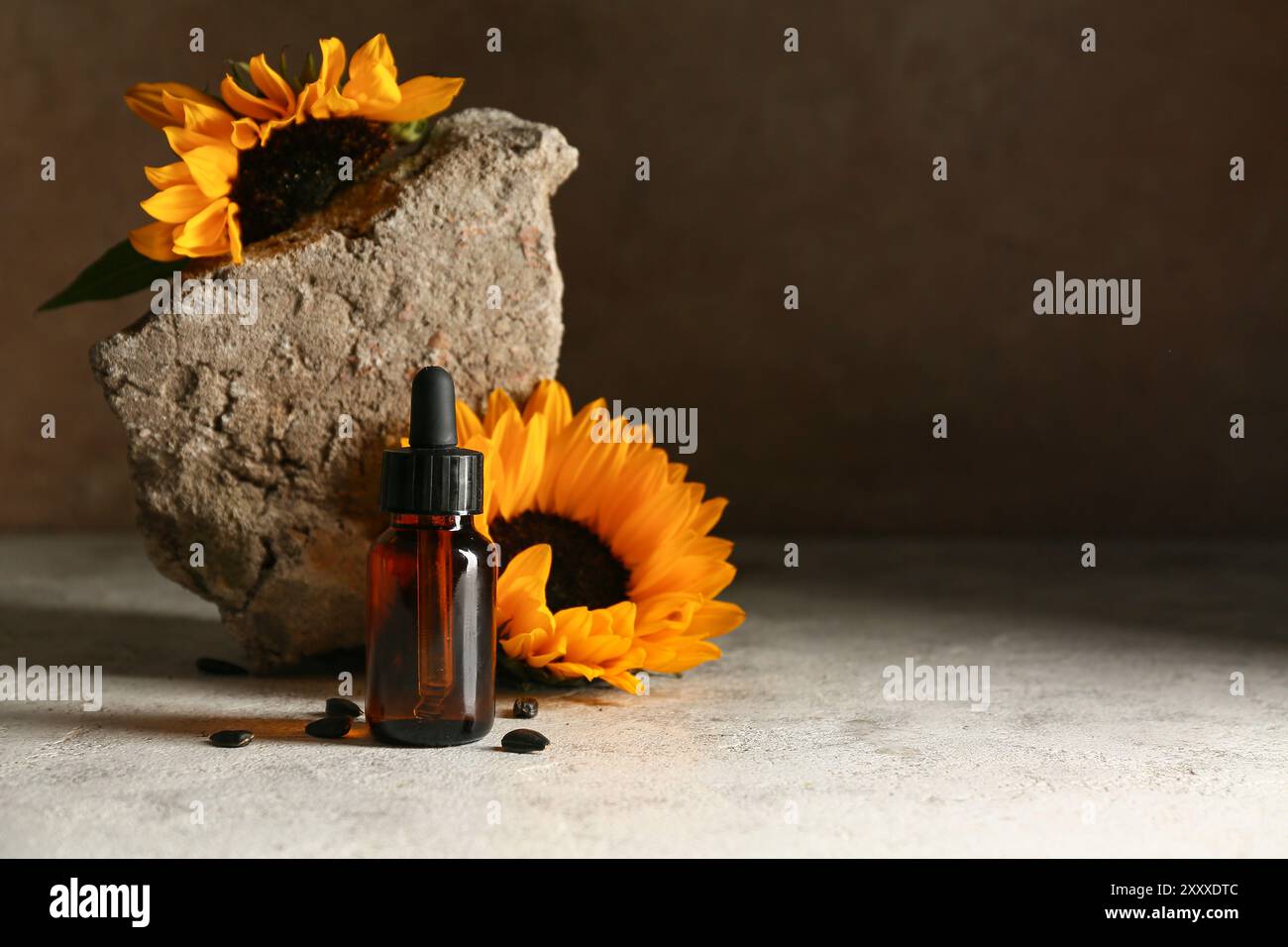 Bottle of essential oil, stone and sunflowers on light table Stock ...