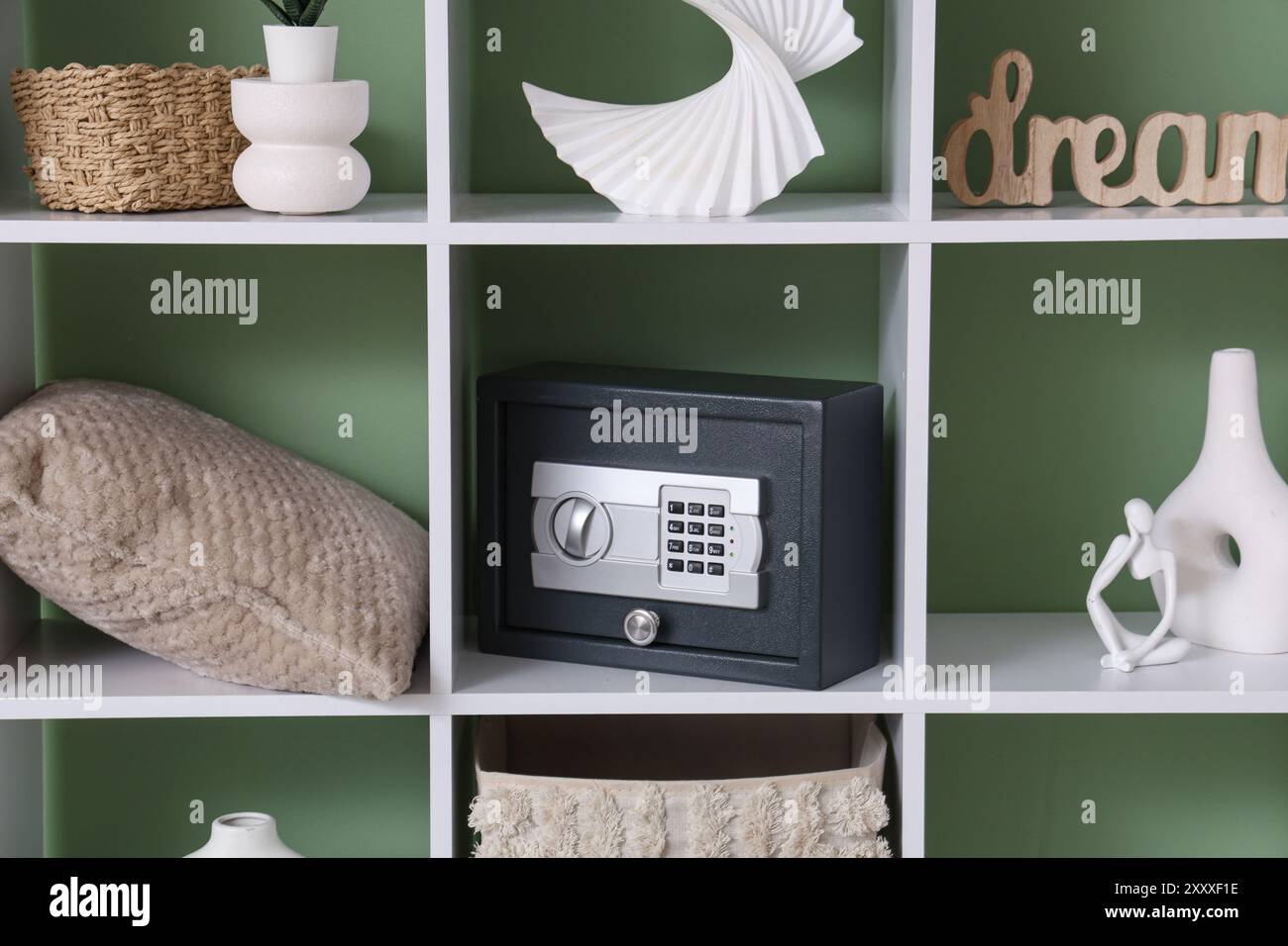 Modern safe and decor on shelves near green wall Stock Photo - Alamy