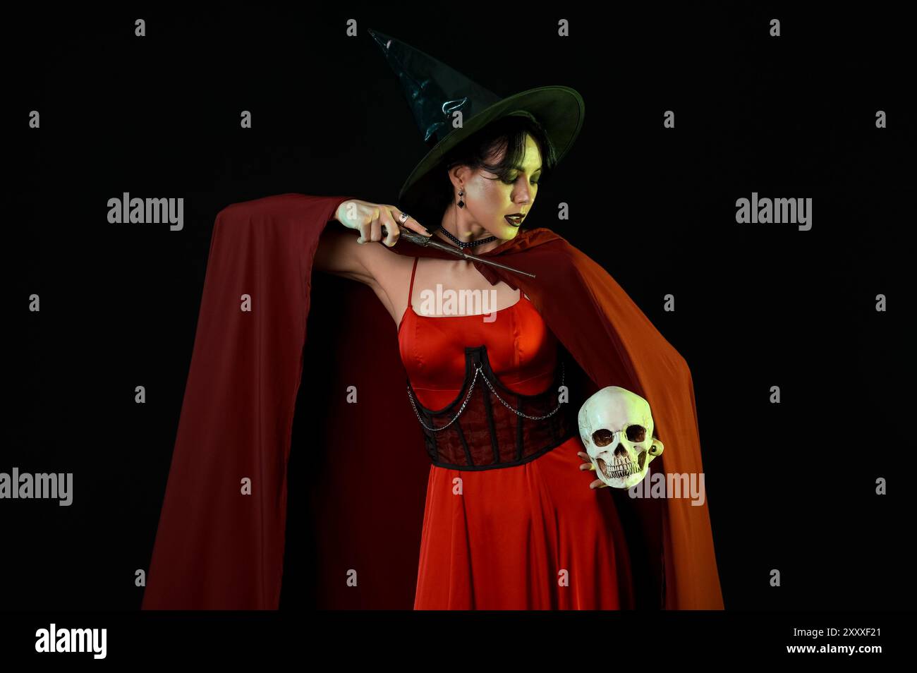 Beautiful young woman dressed as witch for Halloween with human skull ...