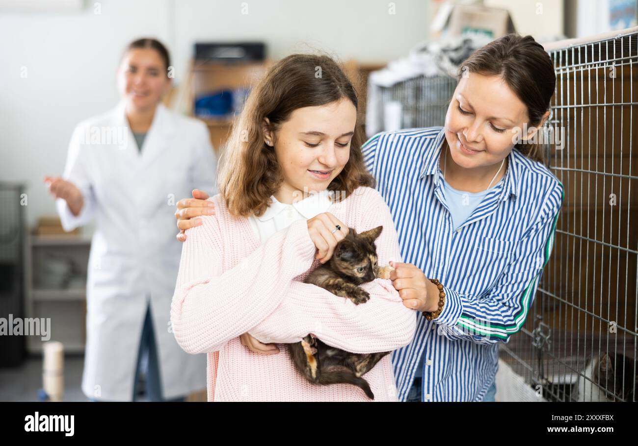 Tween girl with mom holding adopted kitten in animal shelter Stock ...