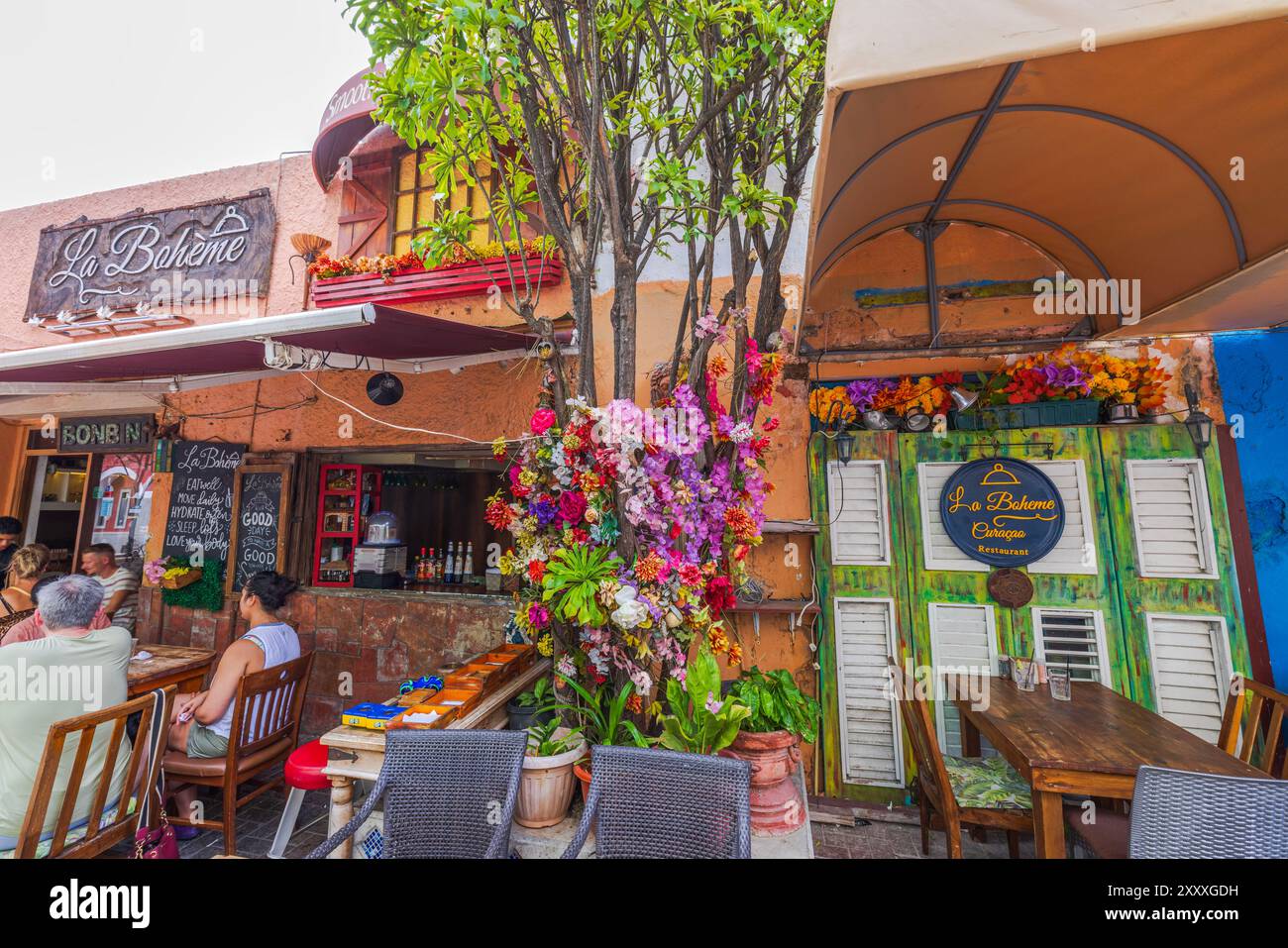 View of outdoor cafe in Curacao with colorful flowers decorating facade ...