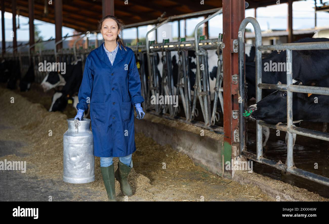 Female dairy farm worker carrying milk can in cowshed Stock Photo - Alamy