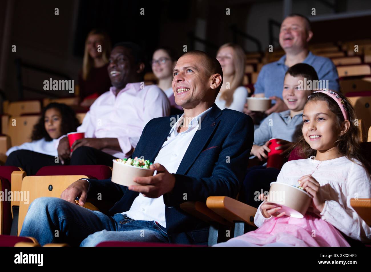 Cheerful family watching a movie and eating popcorn in cinema Stock ...