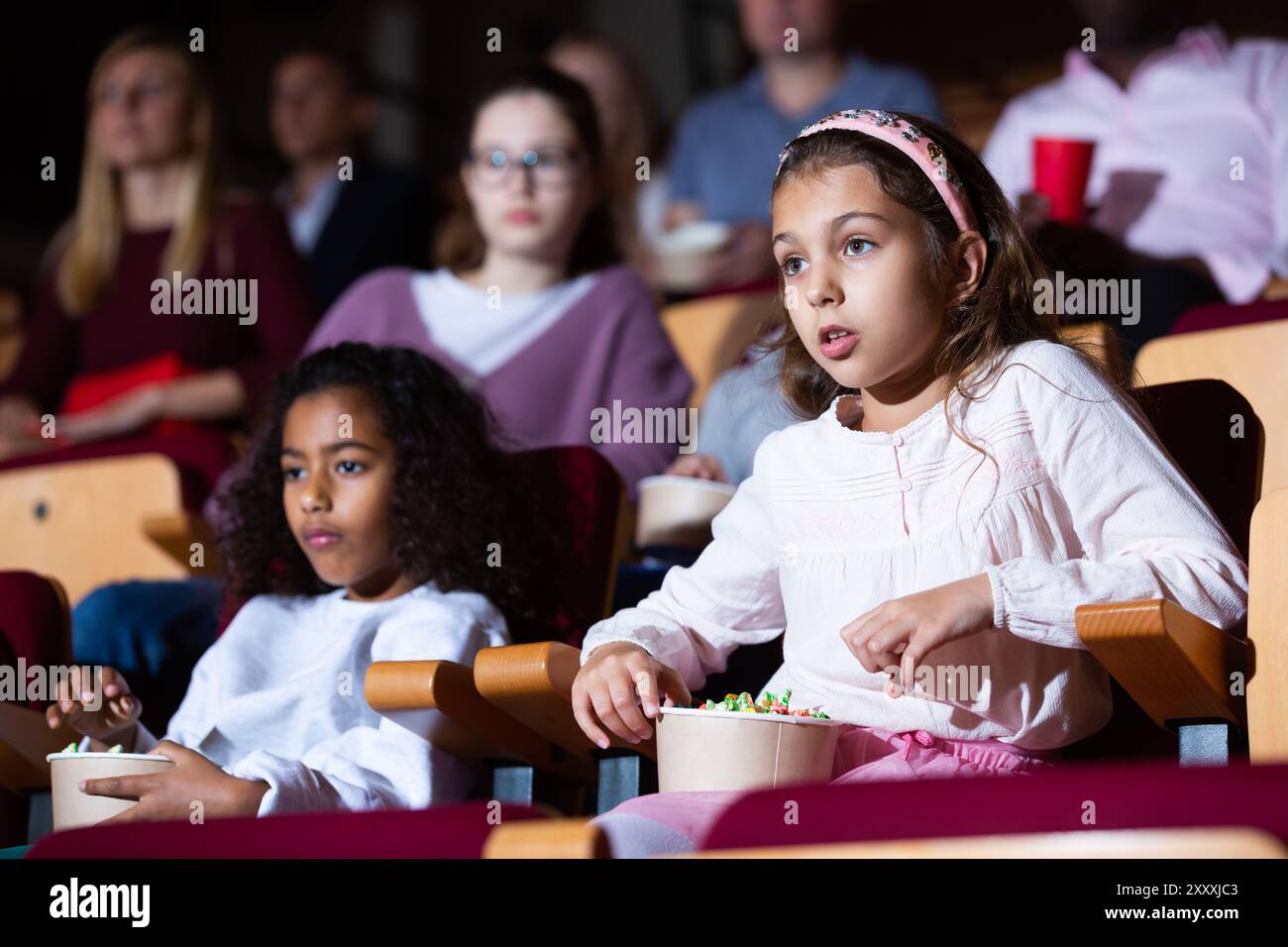 Girls watching a movie and eating popcorn in cinema Stock Photo - Alamy