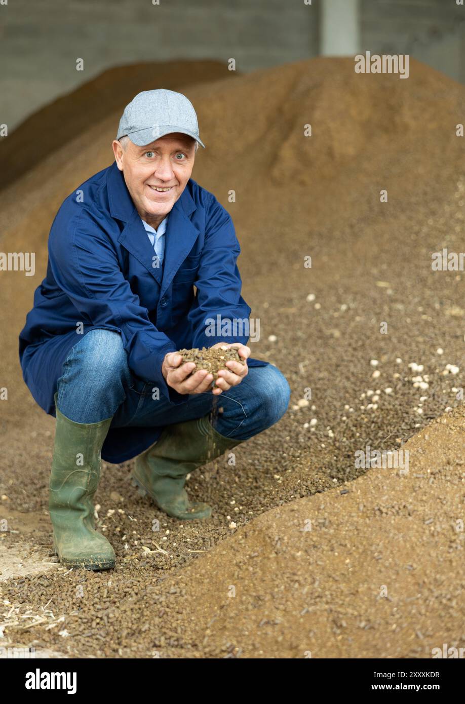 Smiling dairy farm male worker holding rapeseed animal feed Stock Photo ...
