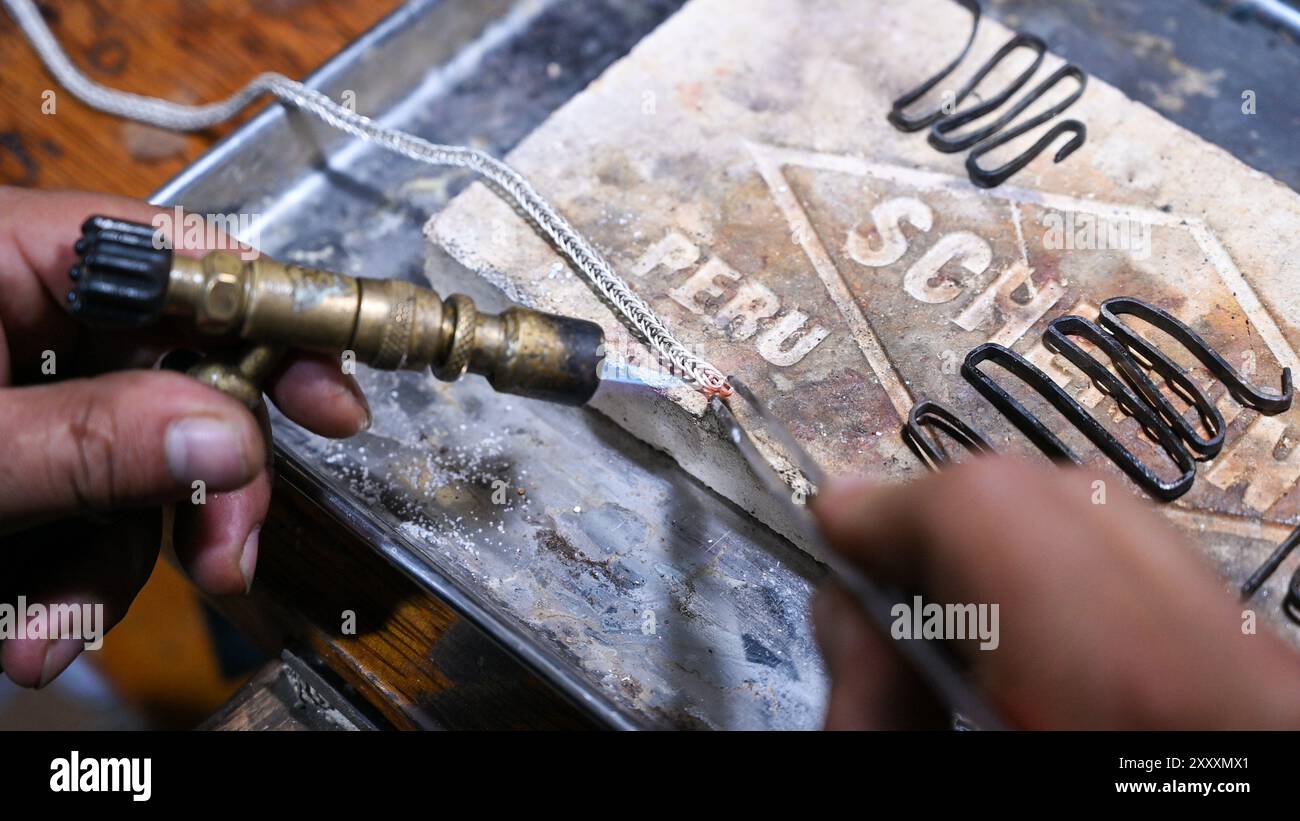 Goldsmith carefully welding a silver chain link using a blowtorch Stock ...