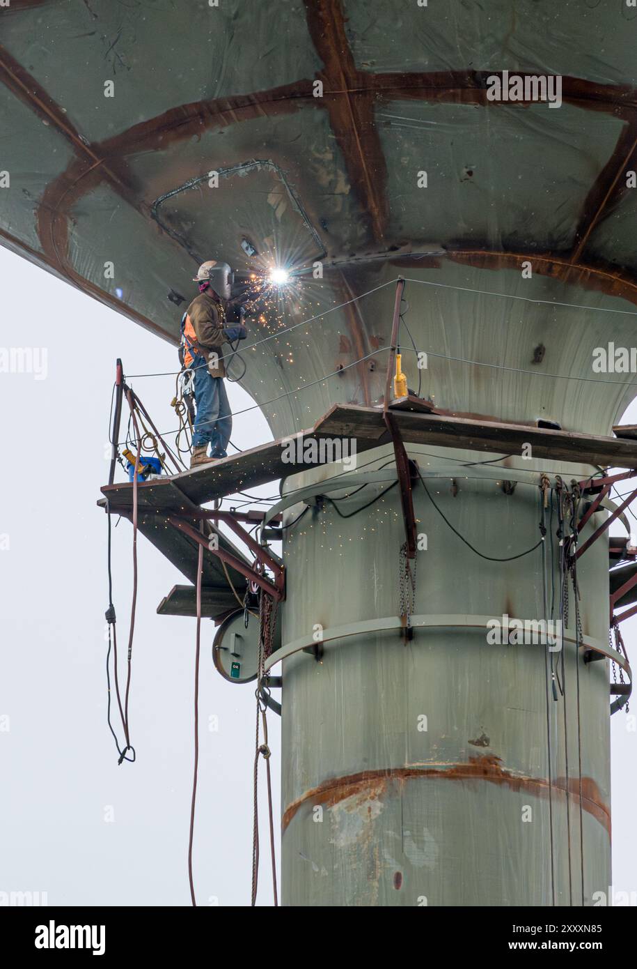 Construction worker welding on a water tower Stock Photo - Alamy