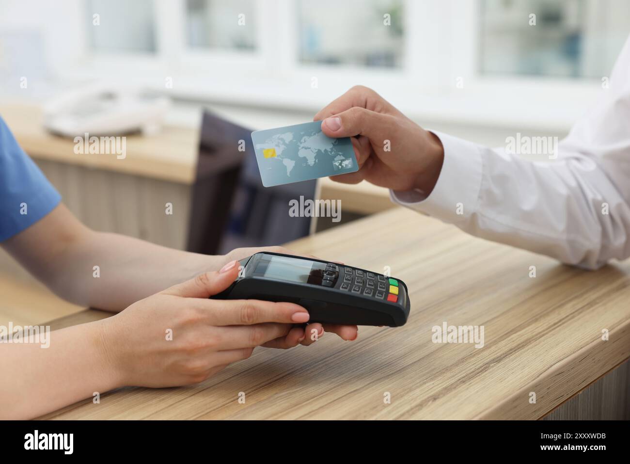 Receptionist taking payment from client via terminal at hospital, closeup Stock Photo - Alamy
