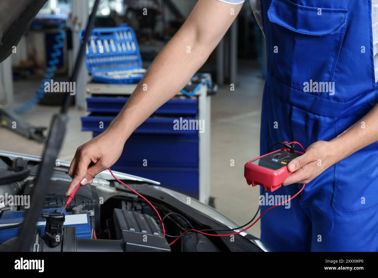 Auto mechanic with multimeter doing diagnostic at automobile repair ...