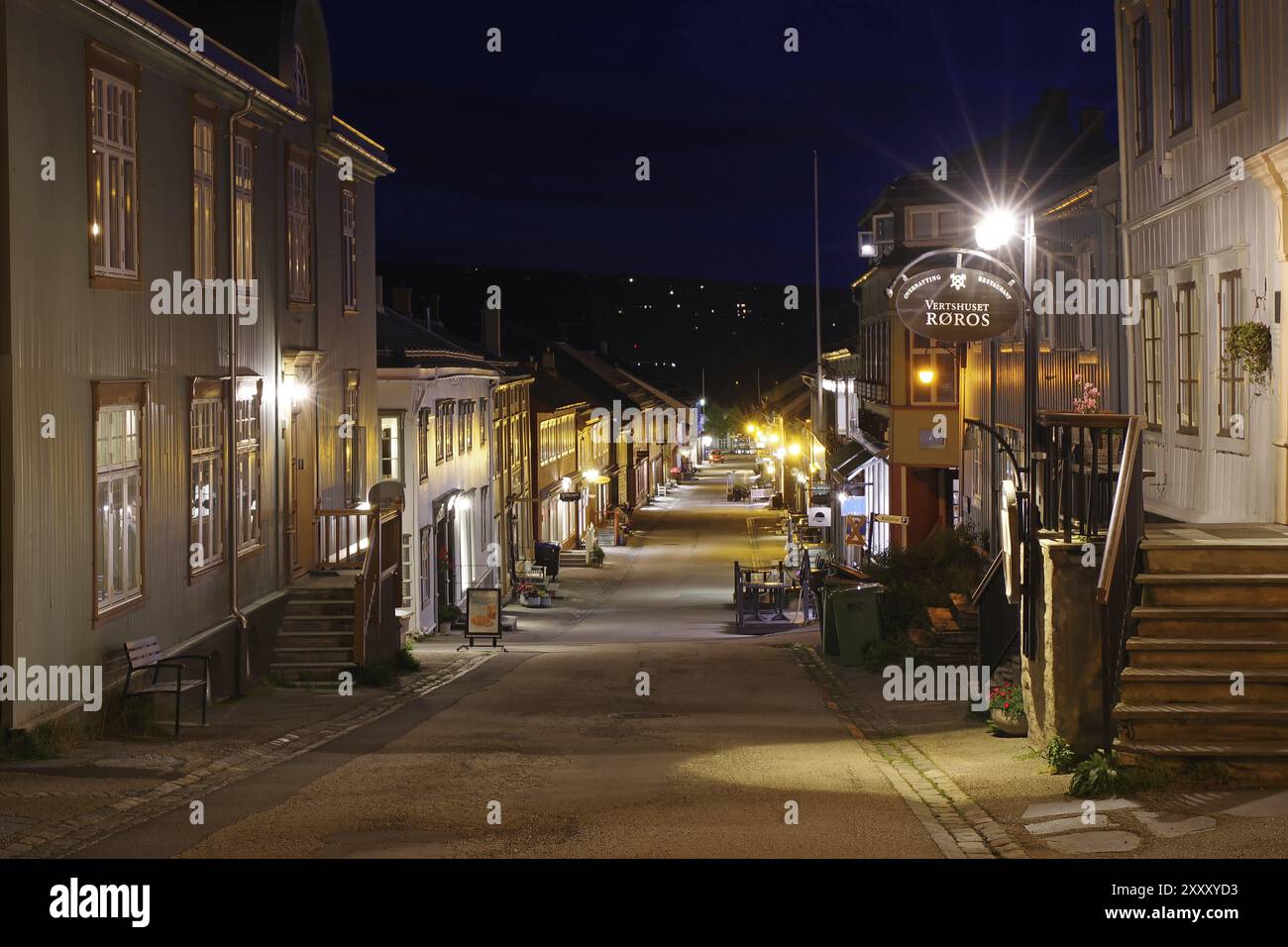 A quiet city street at night with illuminated buildings and a street ...