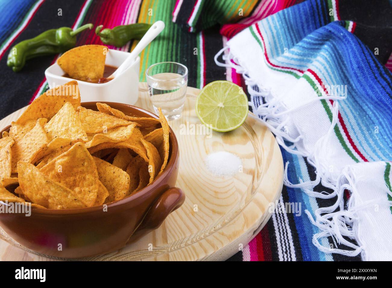 Nachos chips tequila lime and salt over a chopping board with a colored ...
