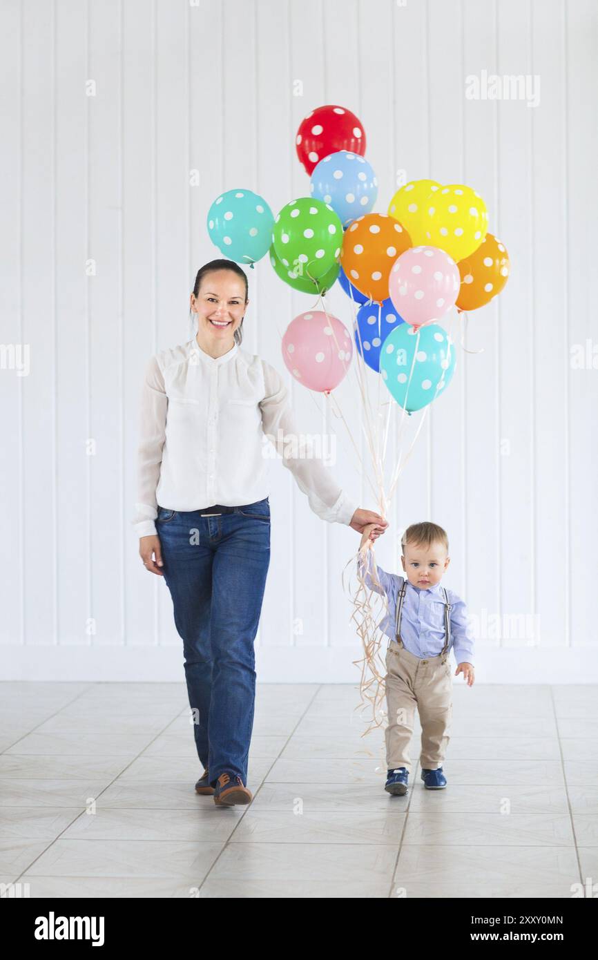 Little boy with his mom holding a large bunch of colored balloons Stock ...