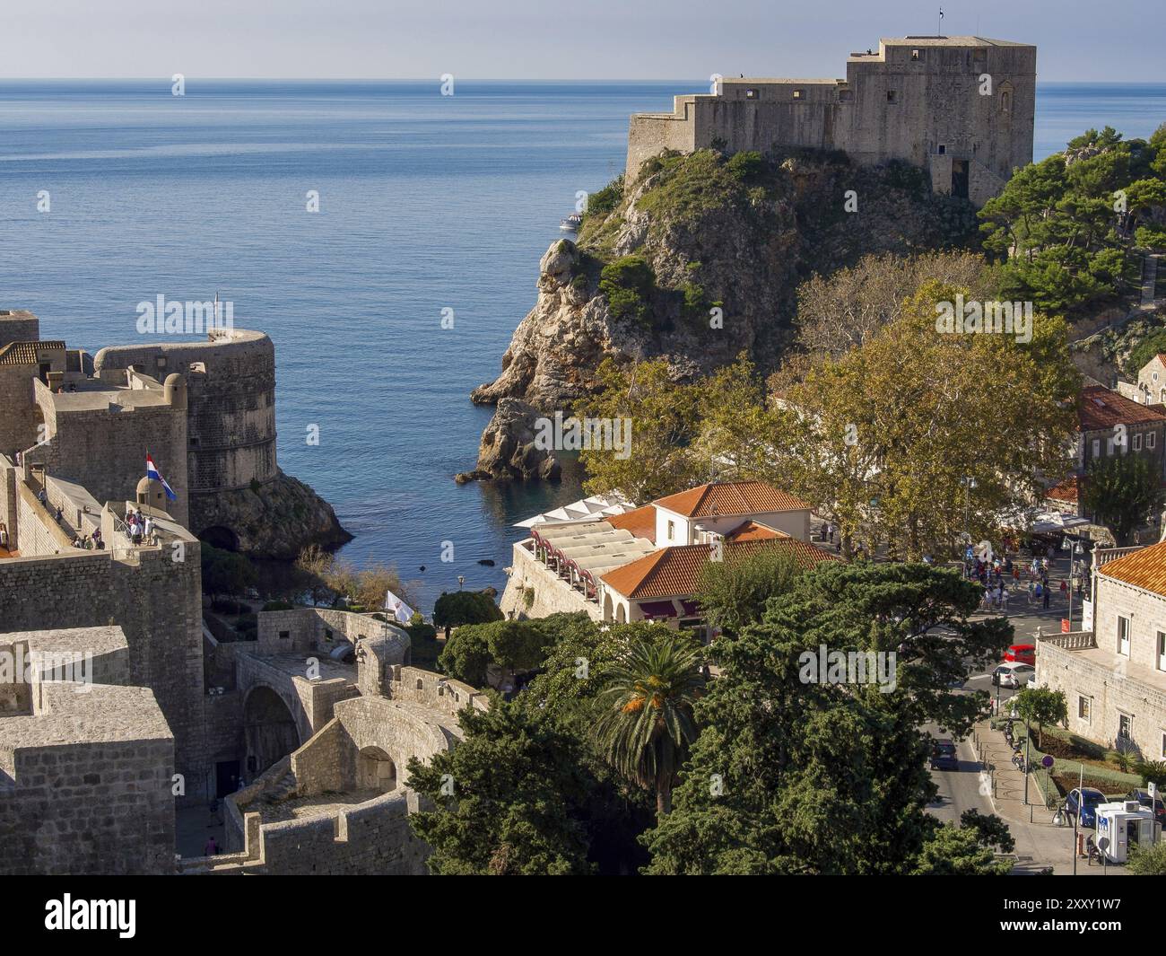 Coastal town with castle on cliffs, surrounded by buildings with red ...
