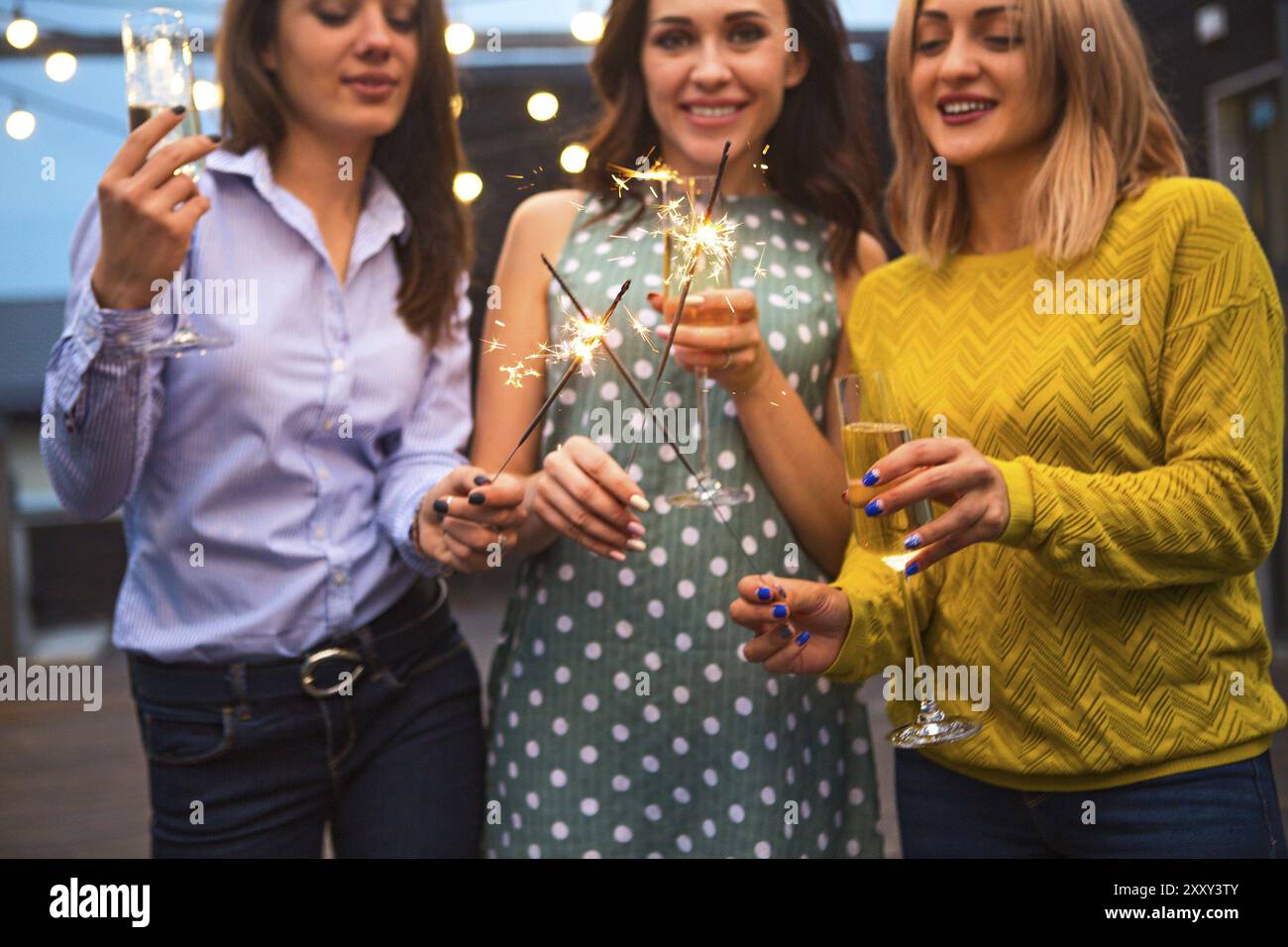Group of partying girls with flutes with sparkling wine and bengal fire ...