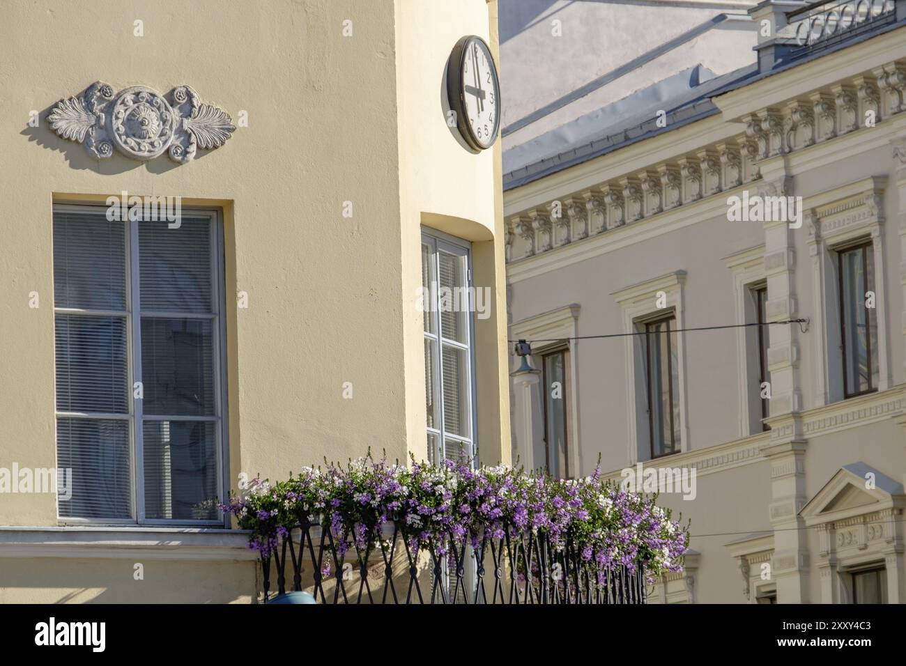 Yellow building with decorative relief and clock, a bay window and a ...