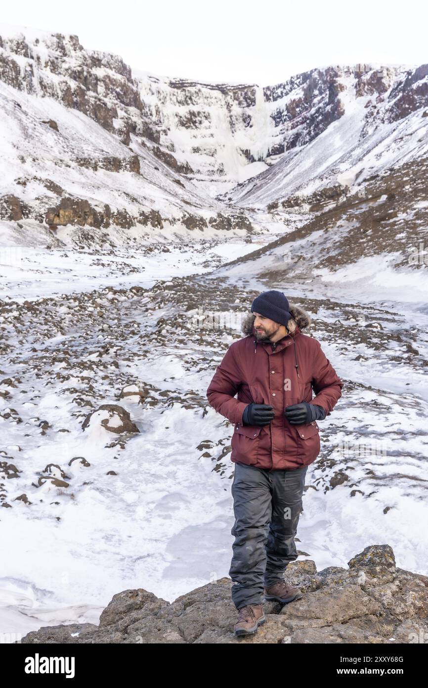 Portrait of a hiker at frozen Hengifoss waterfall in cold Iceland ...