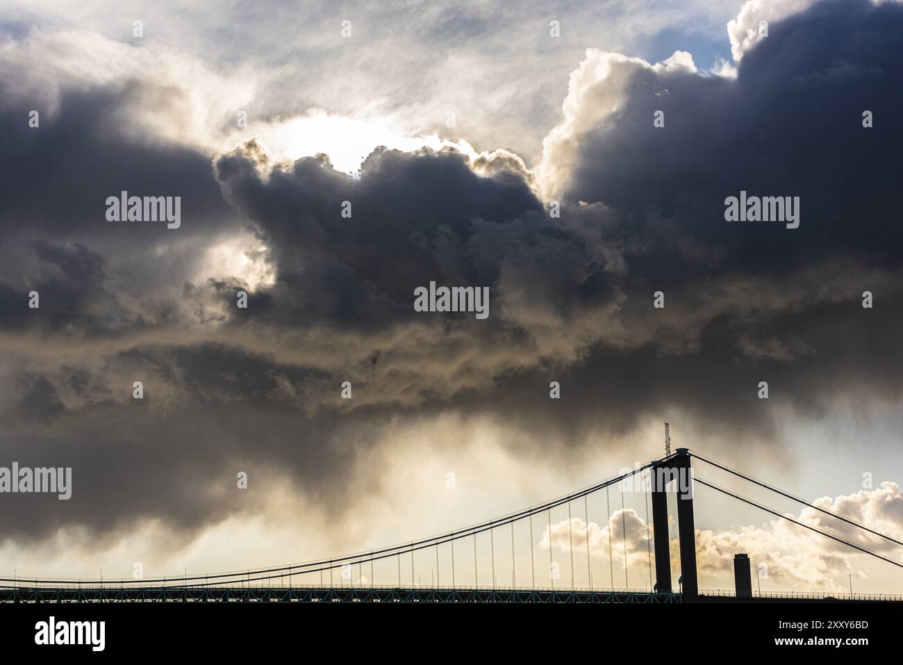 Sun shining through very dark clouds over a suspension bridge Stock ...