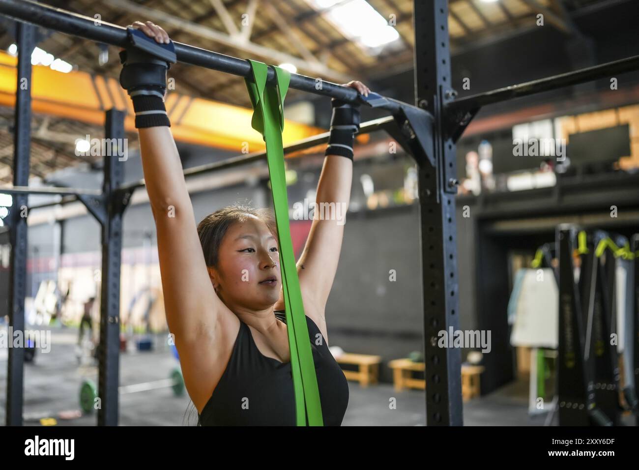Close-up side view photo of a concentrated asian woman doing pull-ups ...