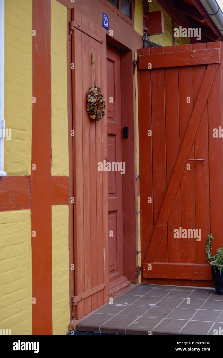 Red wooden house with open door, decorated with a wreath, and yellow ...