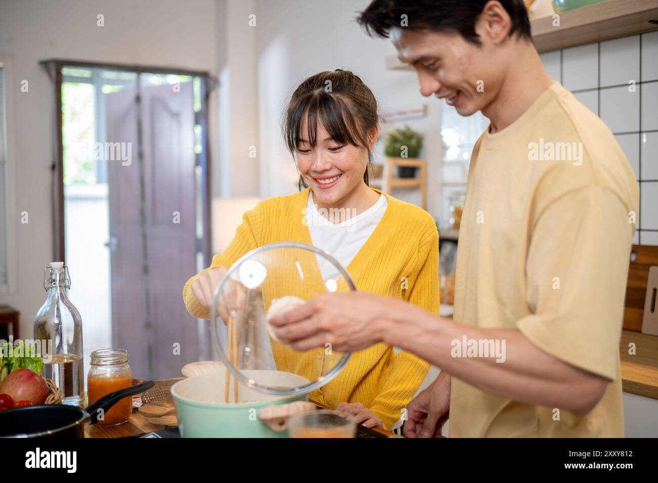 A lovely young Asian couple is enjoying making noodles together in the ...