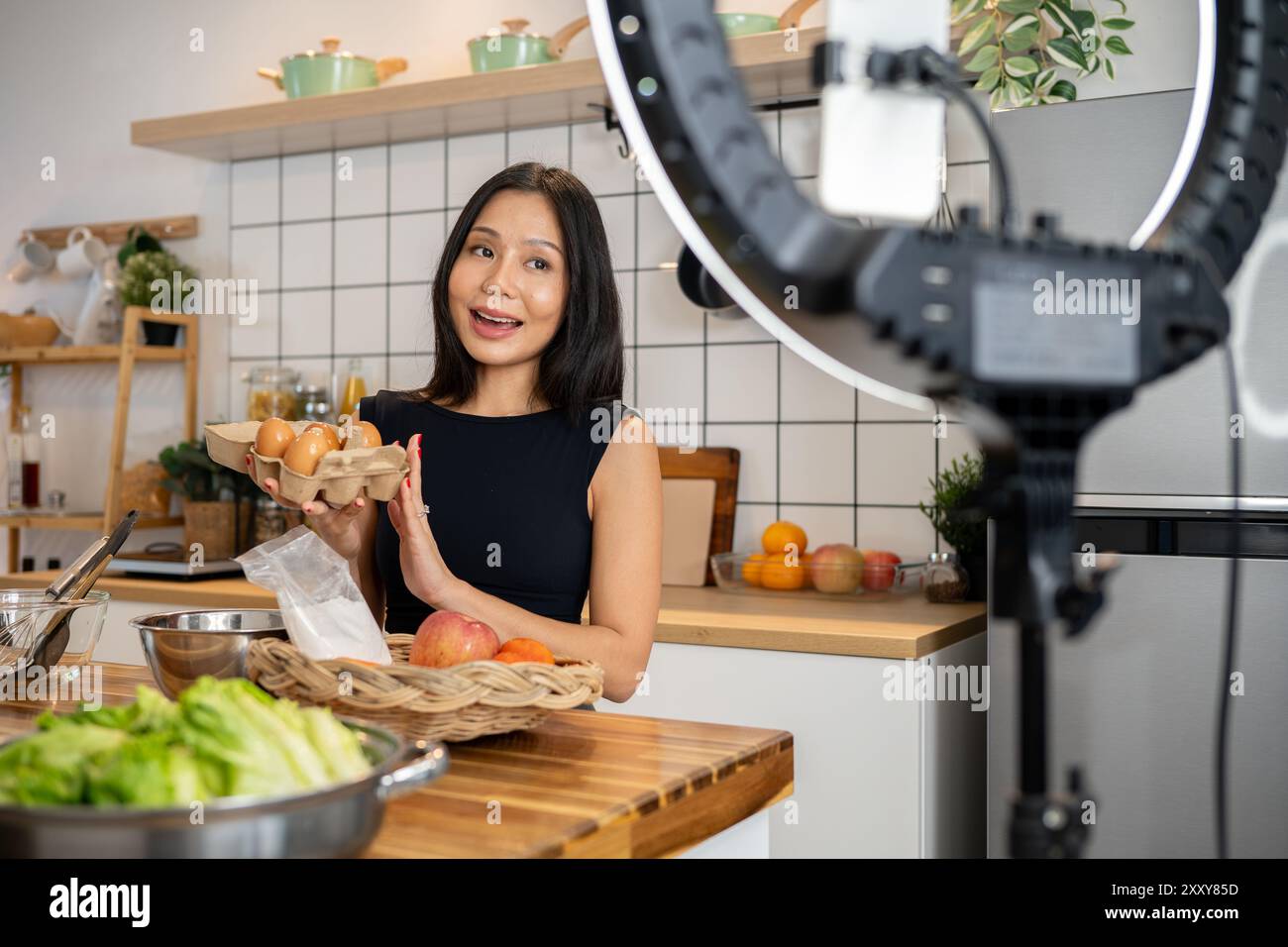 An attractive Asian female food blogger or content creator is cooking ...