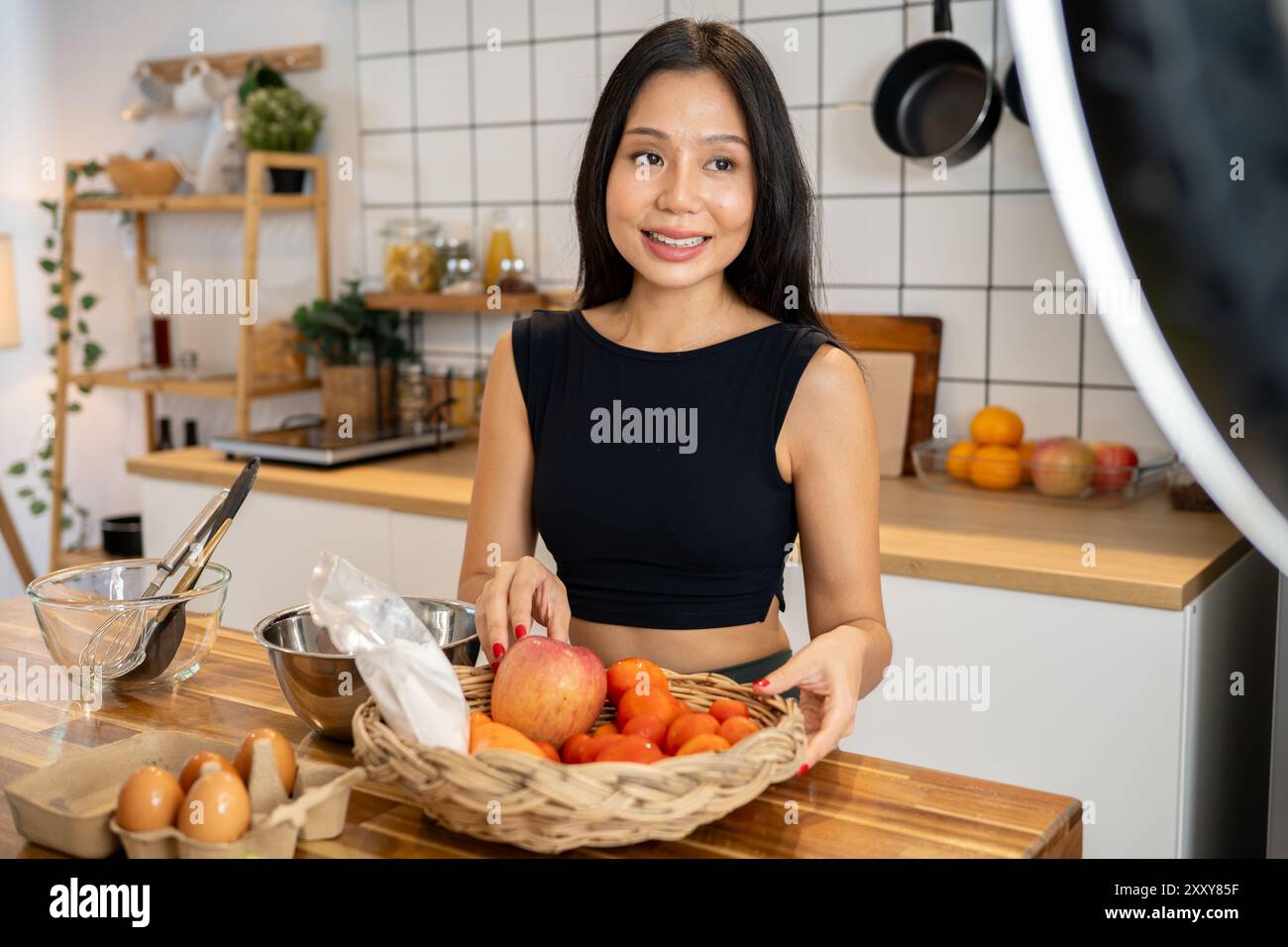 An attractive Asian female food blogger is cooking in front of the ...
