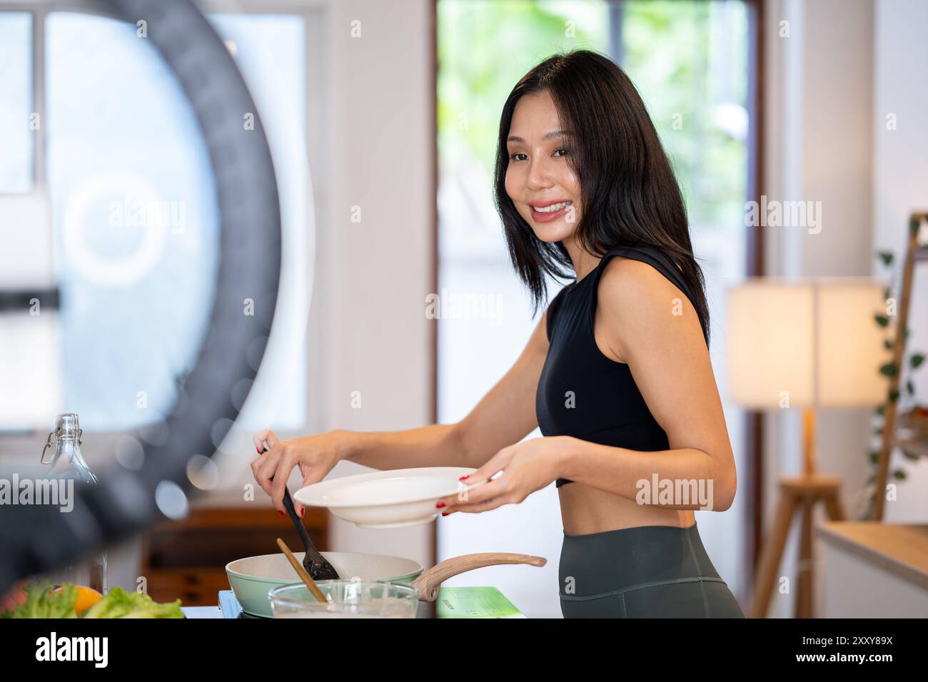 An attractive Asian female food blogger is cooking in front of the ...