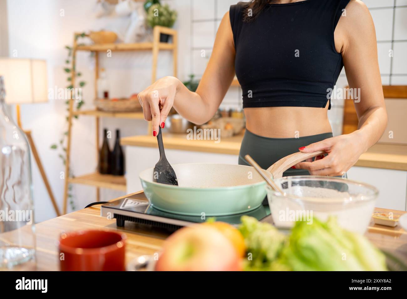 A cropped image of a slim, athlete woman in workout attire cooking in ...