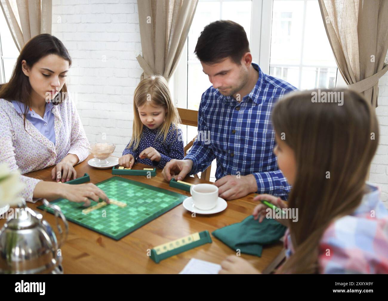 Happy young family plaing board game with two daughters Stock Photo - Alamy