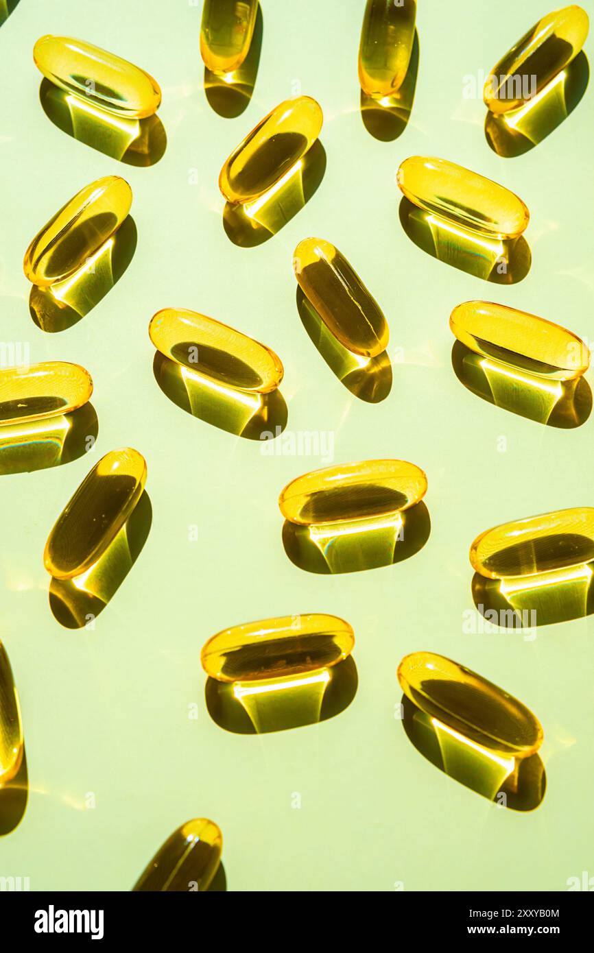 Yellow translucent vitamin capsules arranged on green background and ...