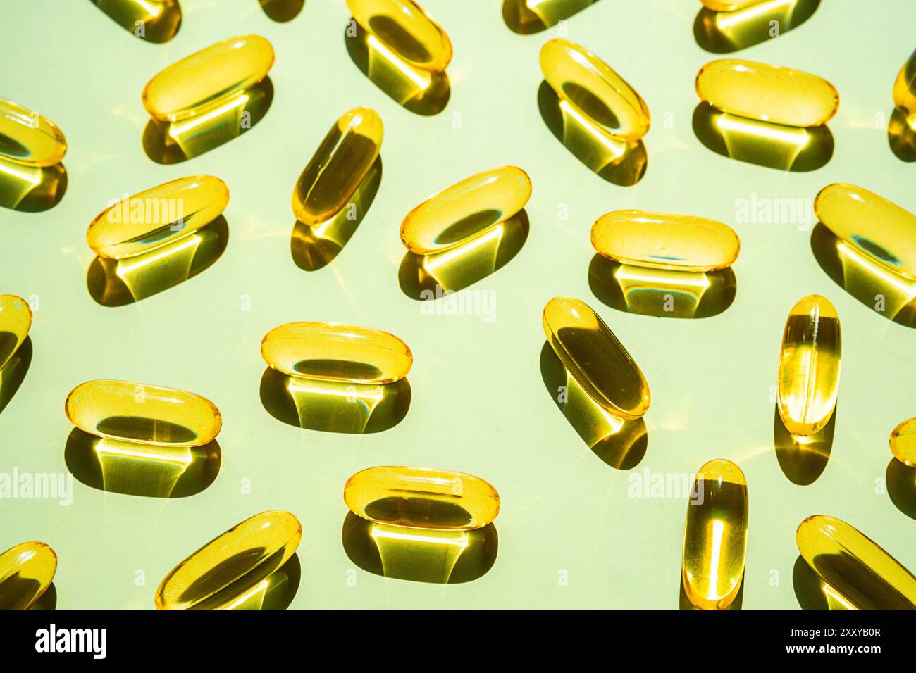 Yellow translucent vitamin capsules arranged on green background and ...
