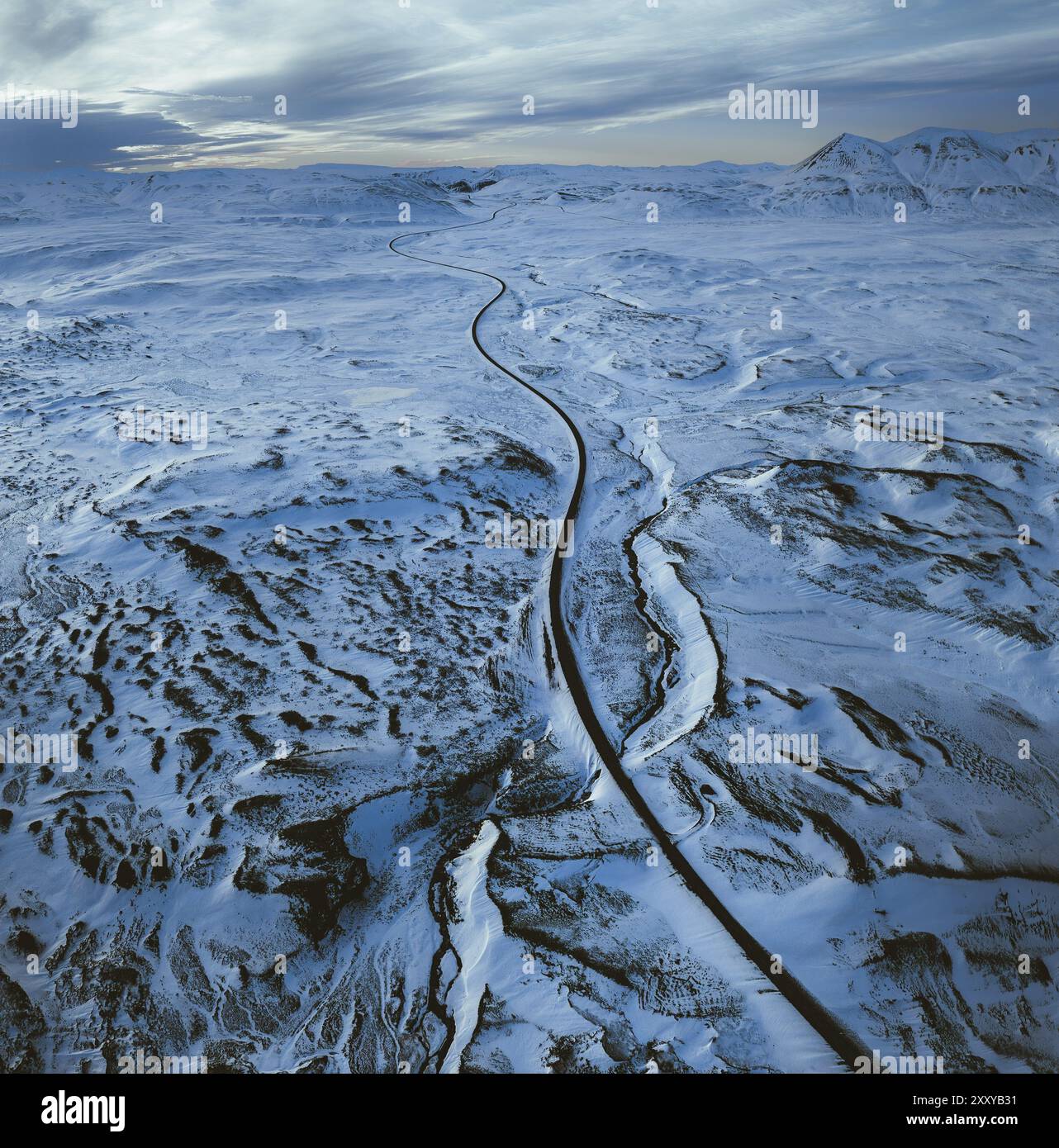 Aerial view of a long road winding through a vast snowy landscape with ...