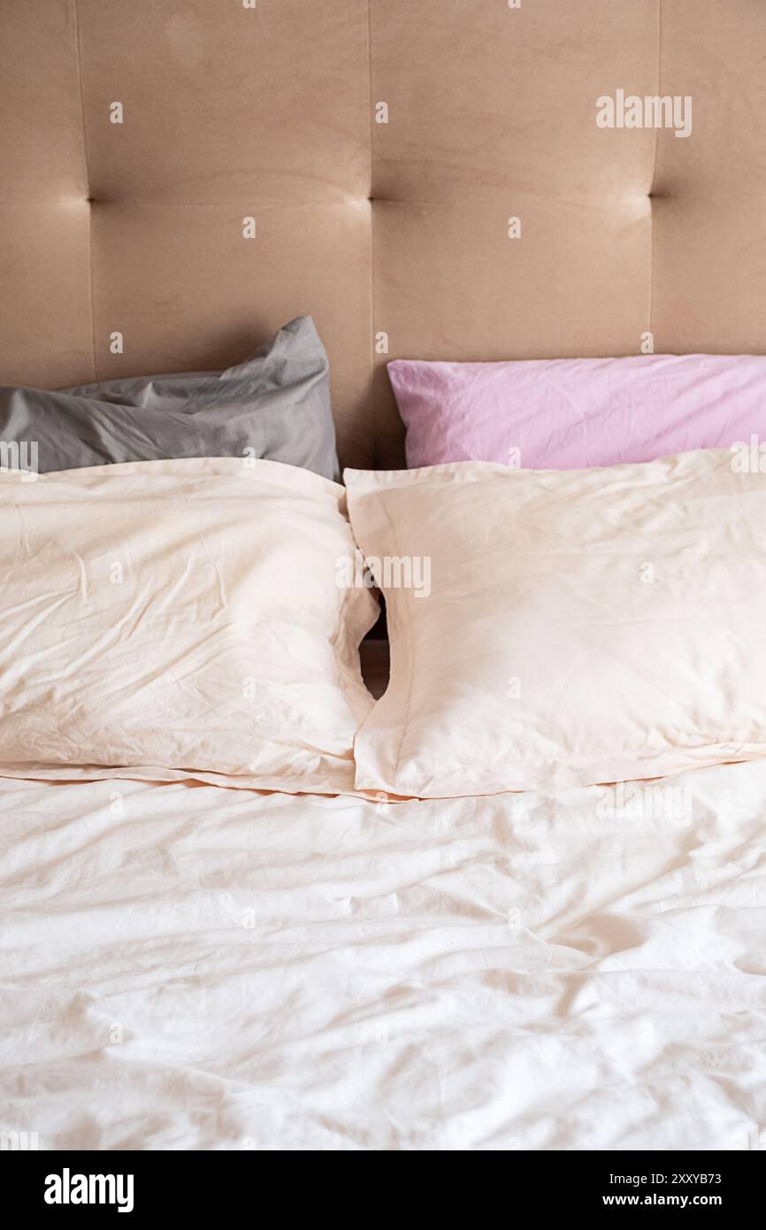 Cozy bed with colorful pillows and beige headboard. Neat and inviting ...