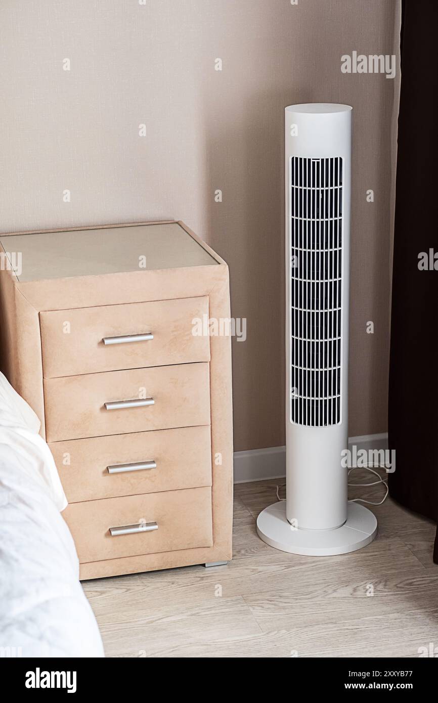 Modern bedroom with sleek tower fan and beige nightstand Stock Photo ...