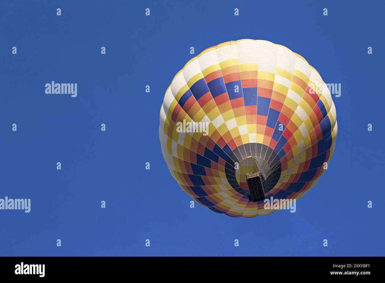 Colorful hot-air balloon in flight seen from below against a blue sky ...