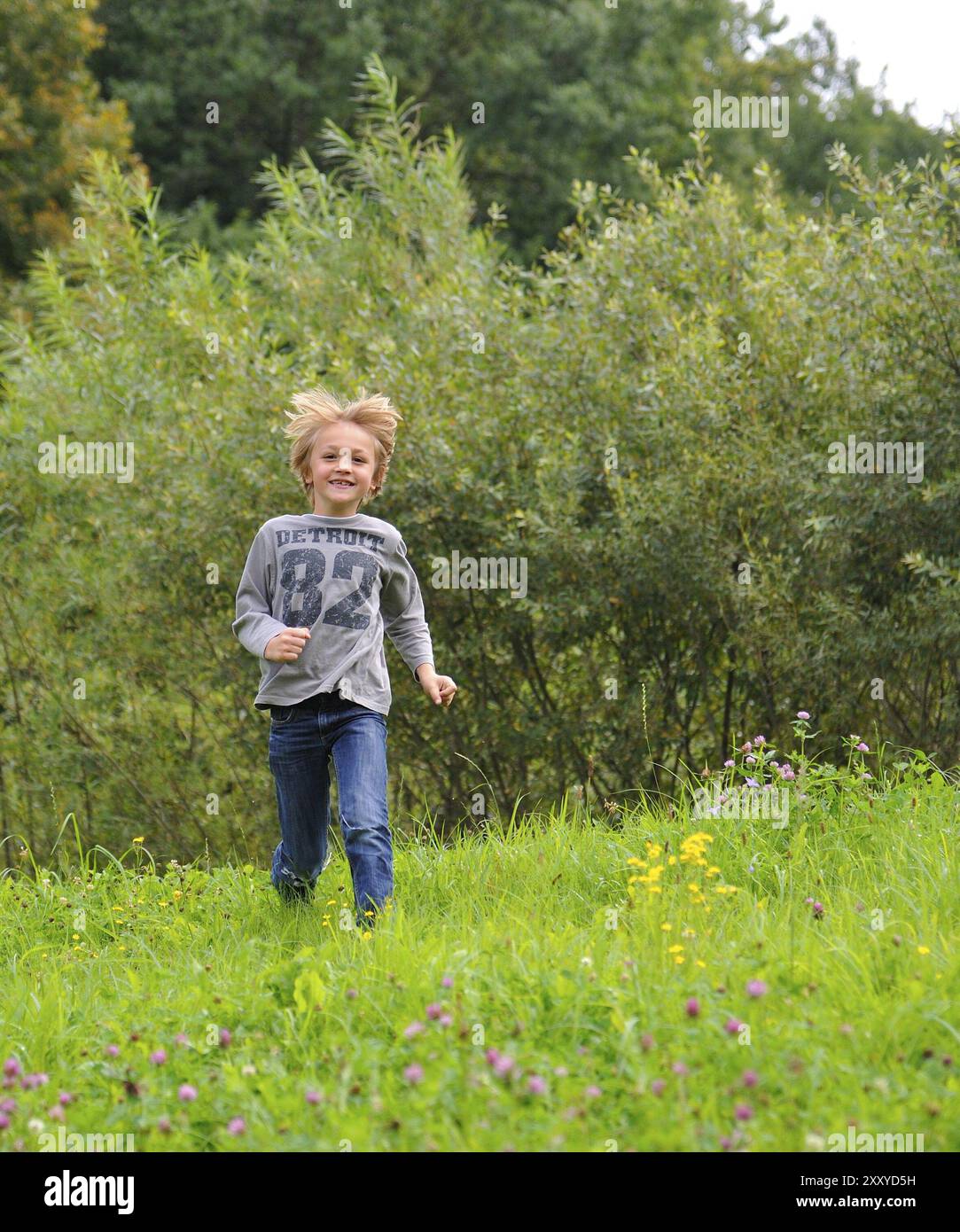 Little boy running outdoors on a meadow. Blond boy running across a ...