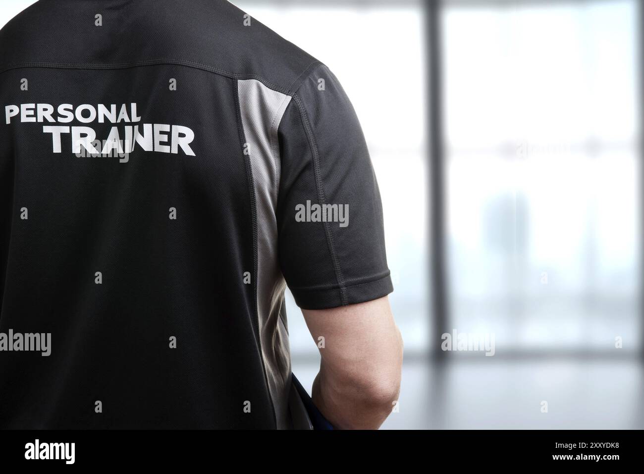 Personal Trainer, with his back facing the camera, looking at a gym ...