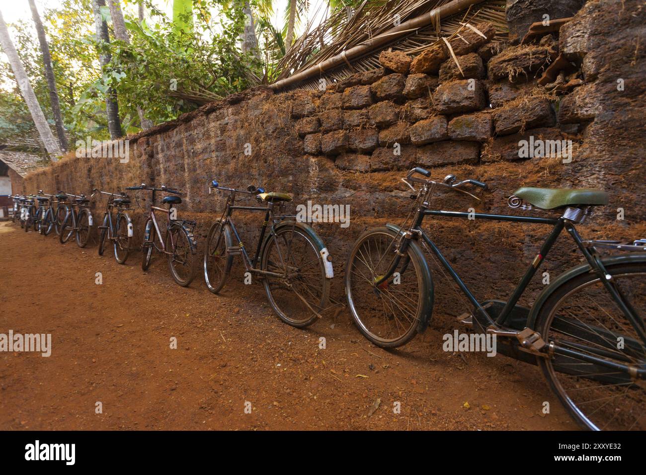 A row of Idnian bicycles line the stone wall of a rural dirt road in ...