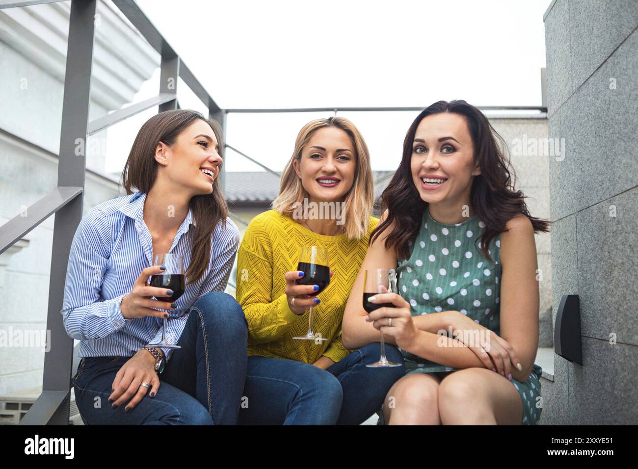 Three young happy woman laughing, drinking red wine, having fun. Party ...