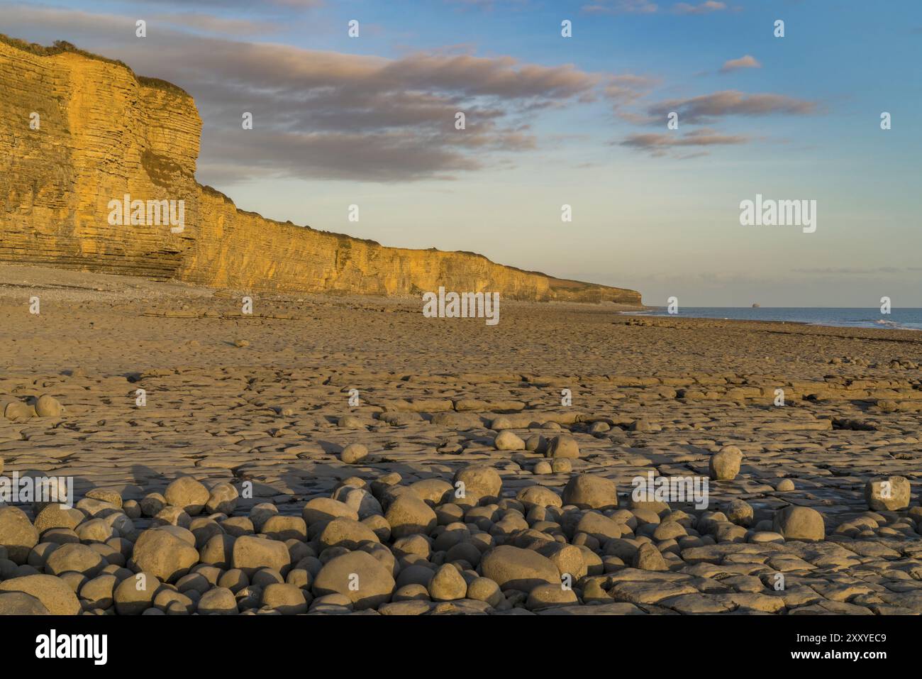 The stones and cliffs of Llantwit Major Beach in the evening sun with ...