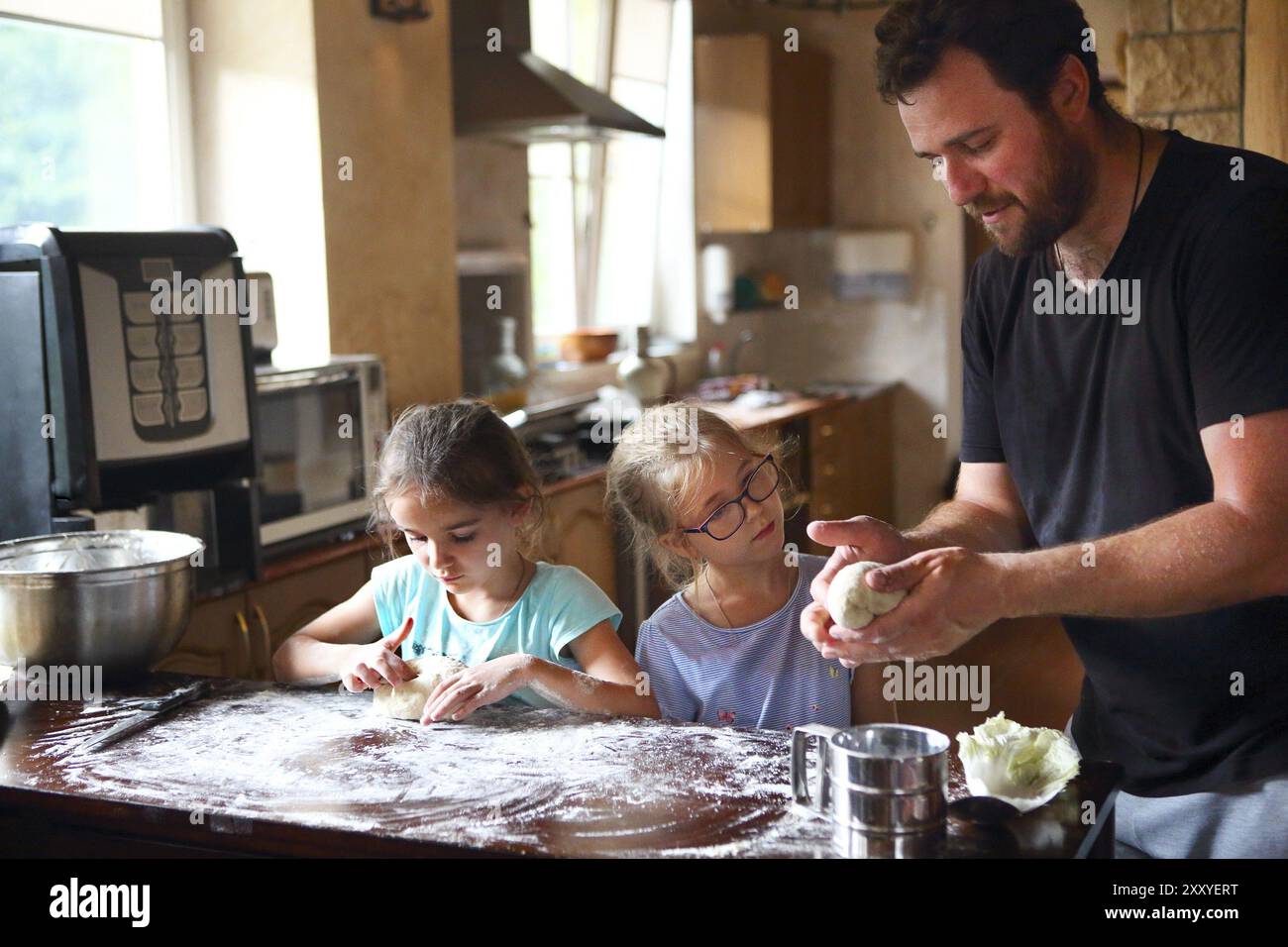 Father and his two little helpers. Children cooking homemade bread with ...