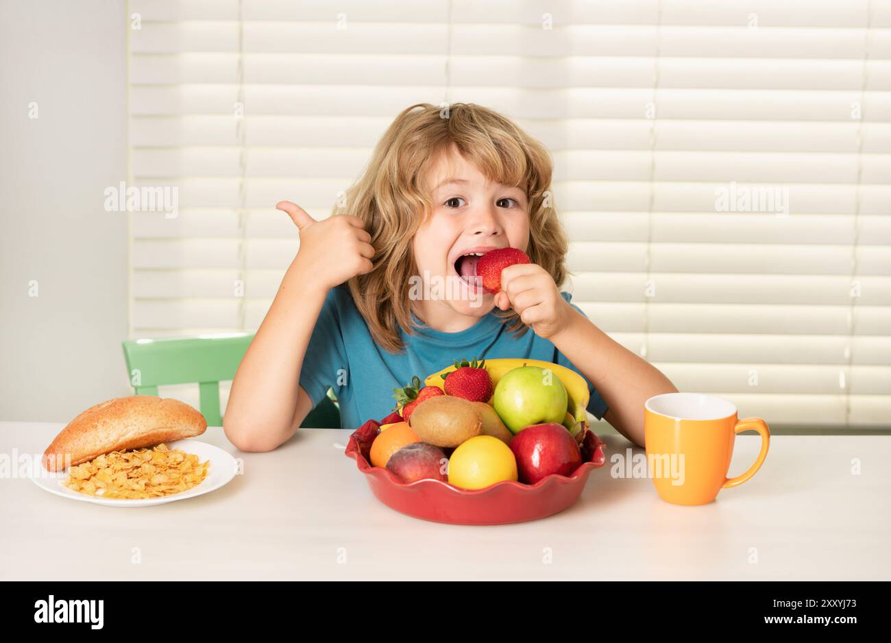 Child with strawberry, summer fruits. Kid preteen boy in the kitchen at ...
