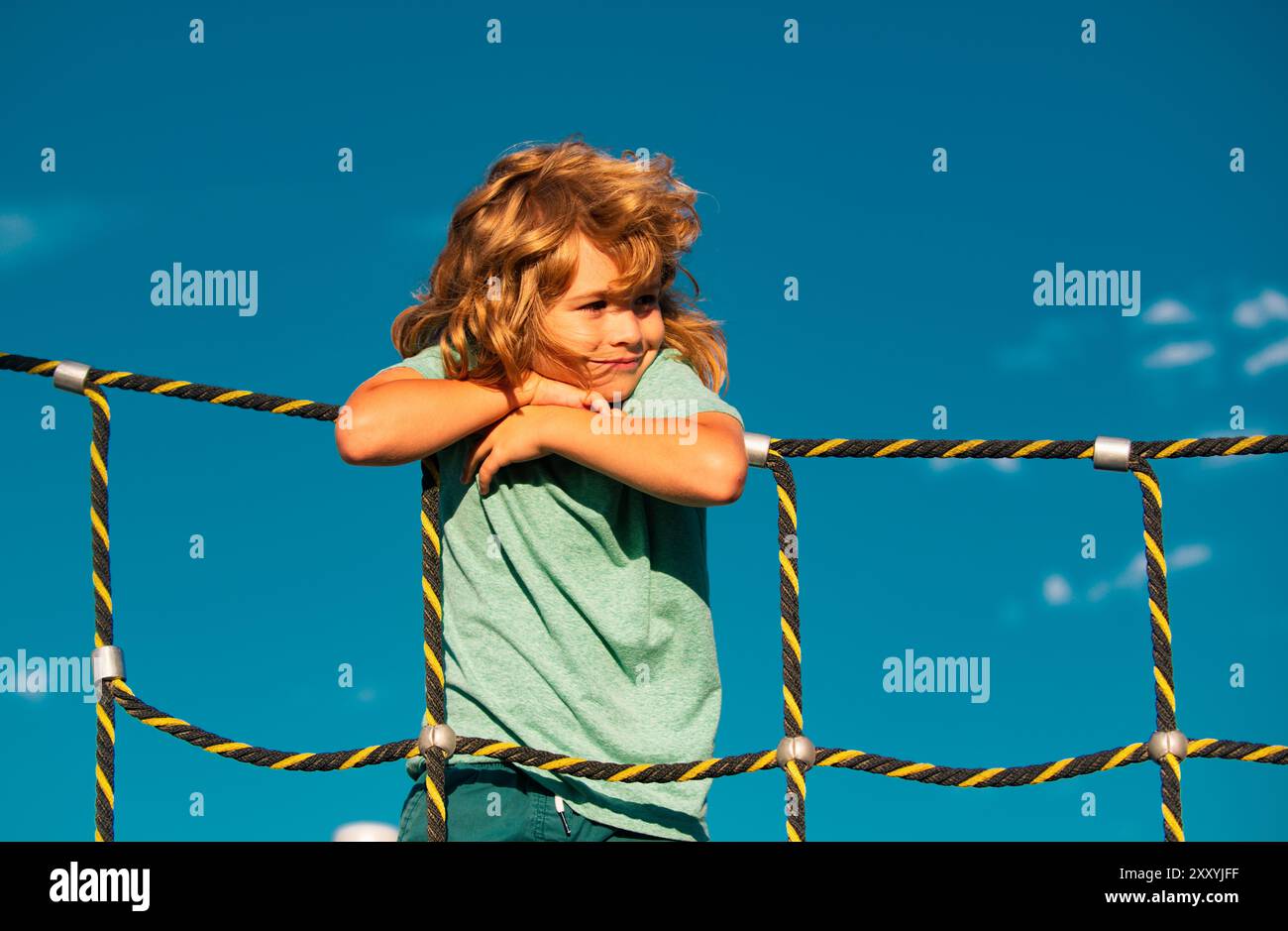 Portrait of cute boy child doing rock climbing in the playbackground ...