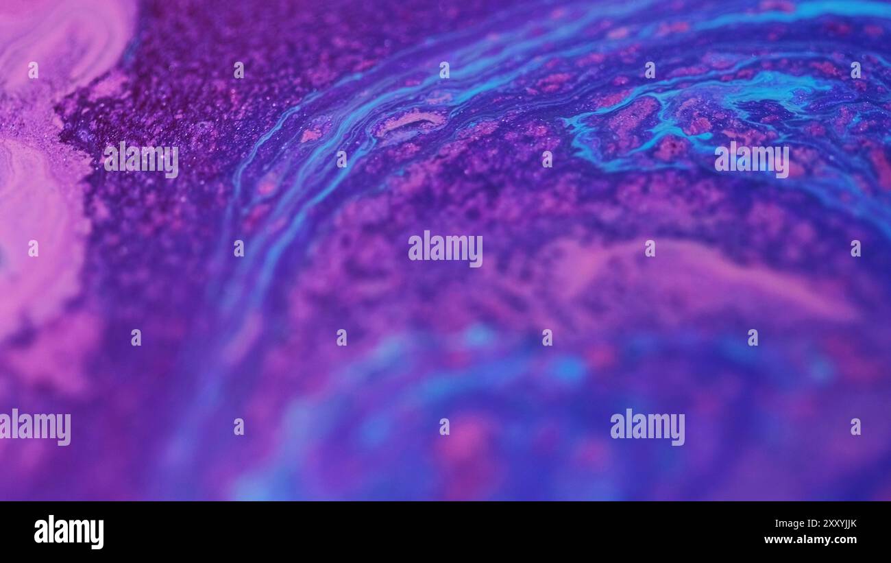Acrylic liquid. Glitter paint. Defocused neon blue purple color ink flow shimmering particles ...