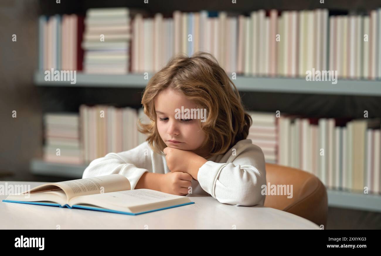 School boy doing homework on desk in school library. Pupil child ...