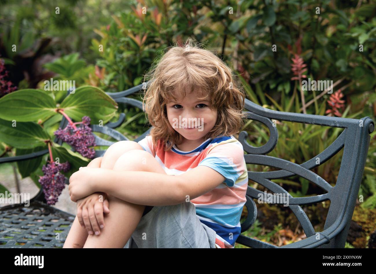 Kid sit on bench. Lifestyle portrait of funny kid outdoors. Summer kids ...